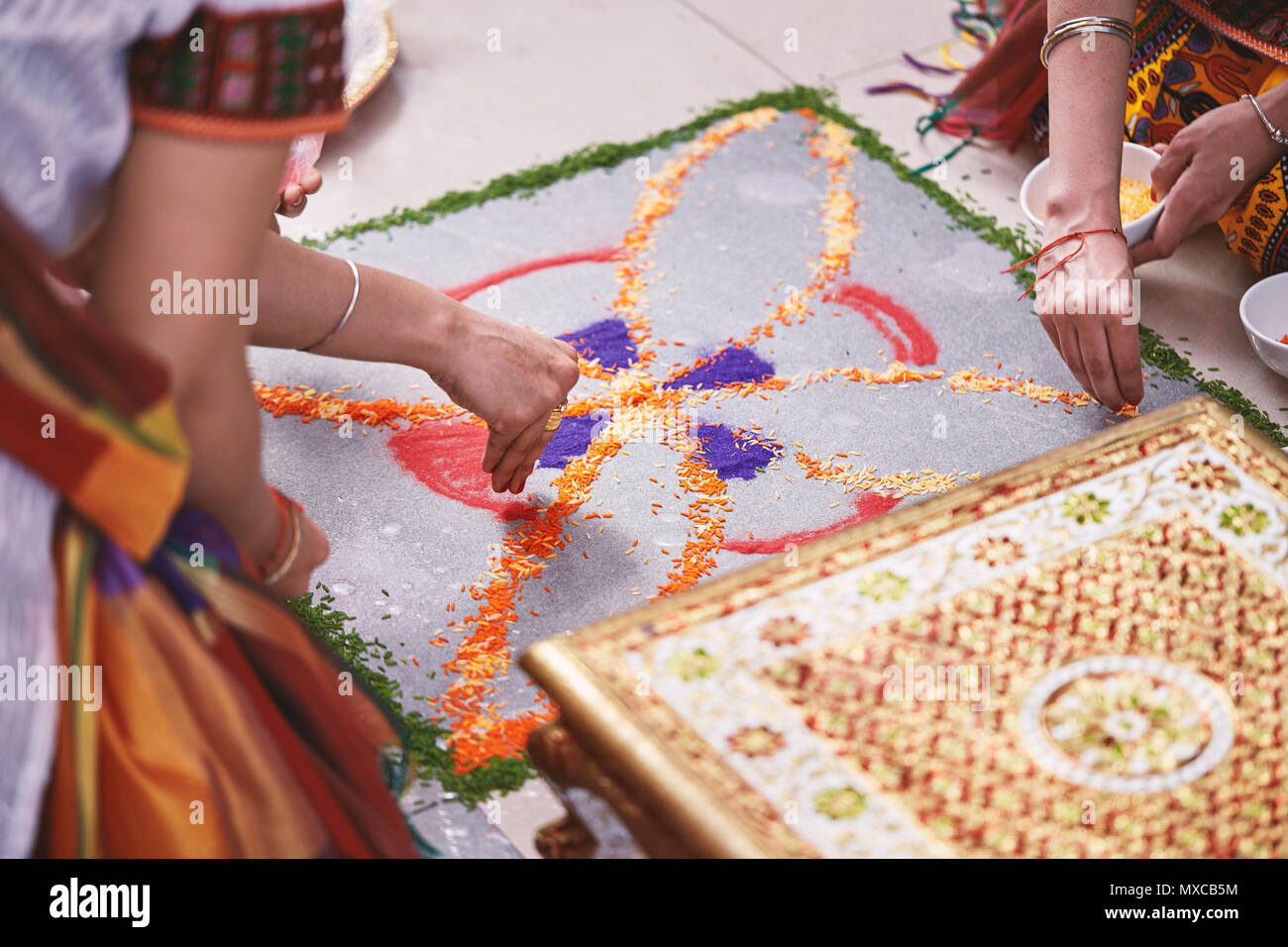 Women helps coloring tradition colorful rice art or sand art (Rangoli ...