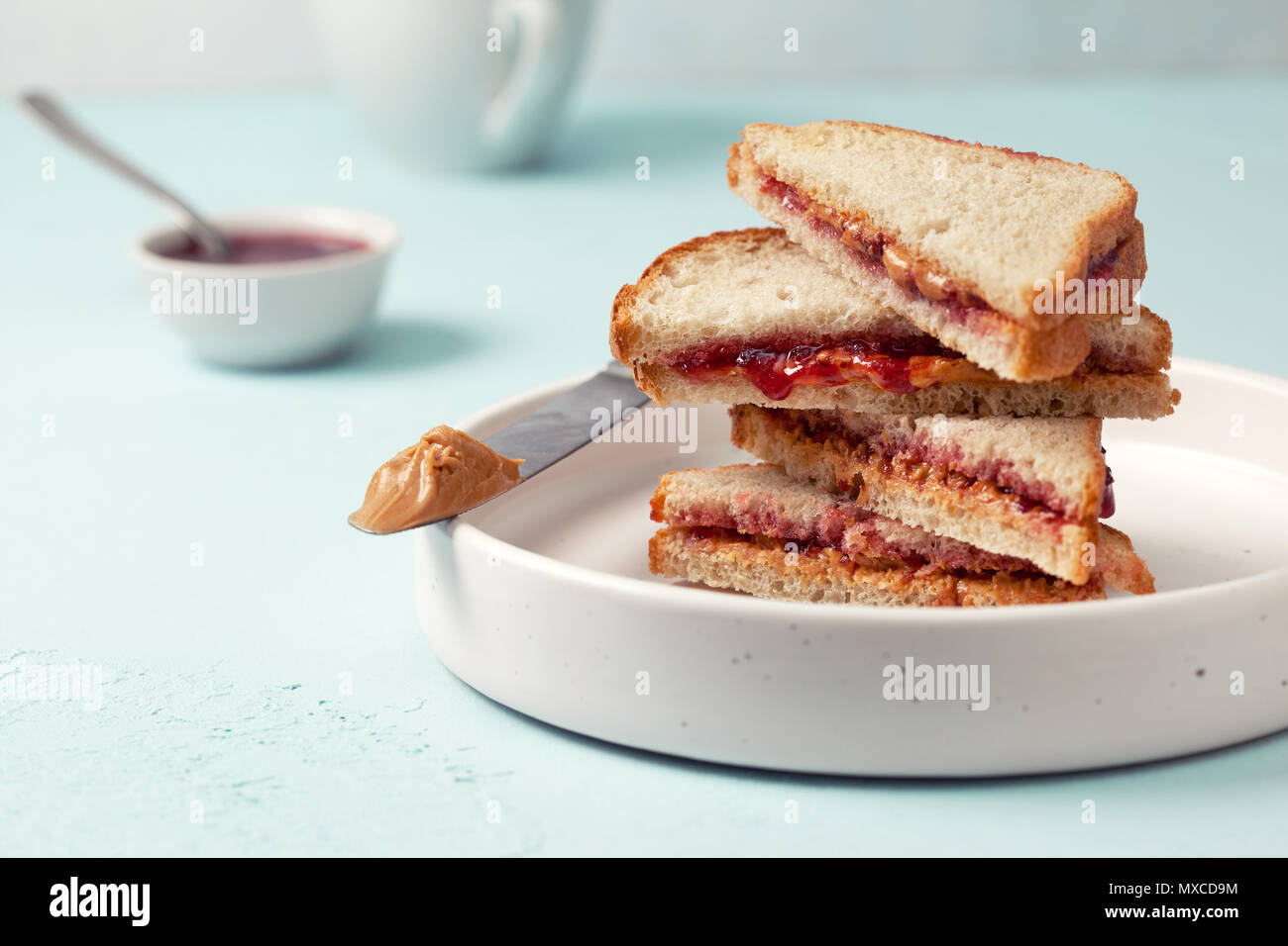 Toast with peanut butter and jam in a white ceramic plate on a blue ...
