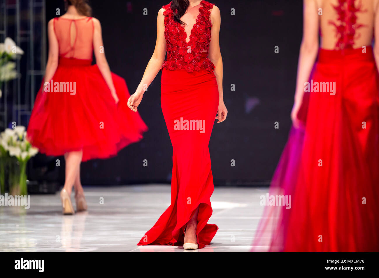 Female models walk the runway in red dresses during a Fashion Show ...