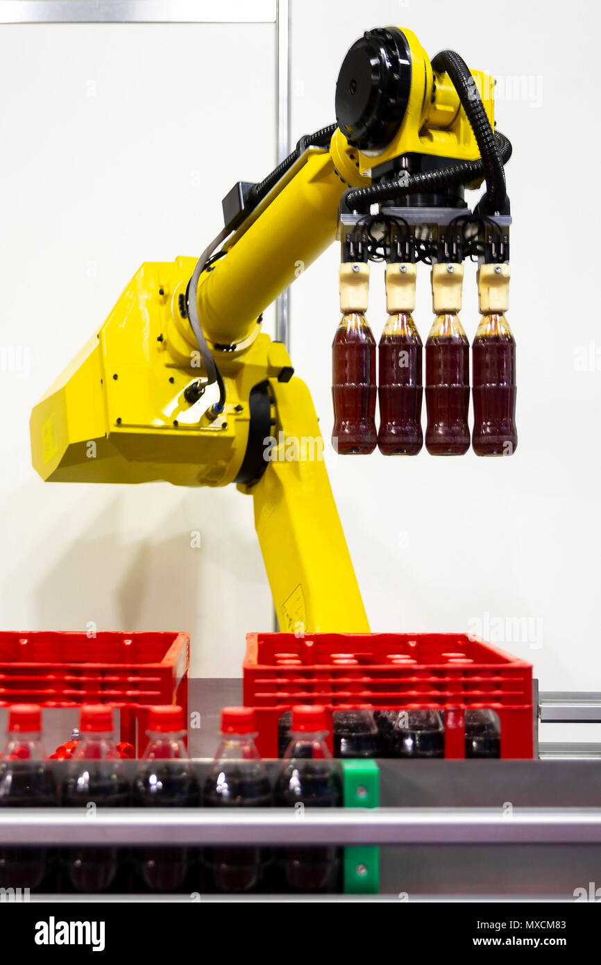 Yellow robotic arm arranges plastic soda bottles in ? packing case ...