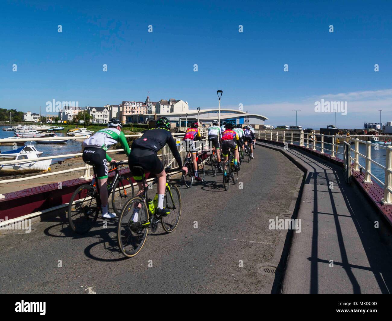 Group of cyclists crossing swing bridge heading towards swimming pool ...