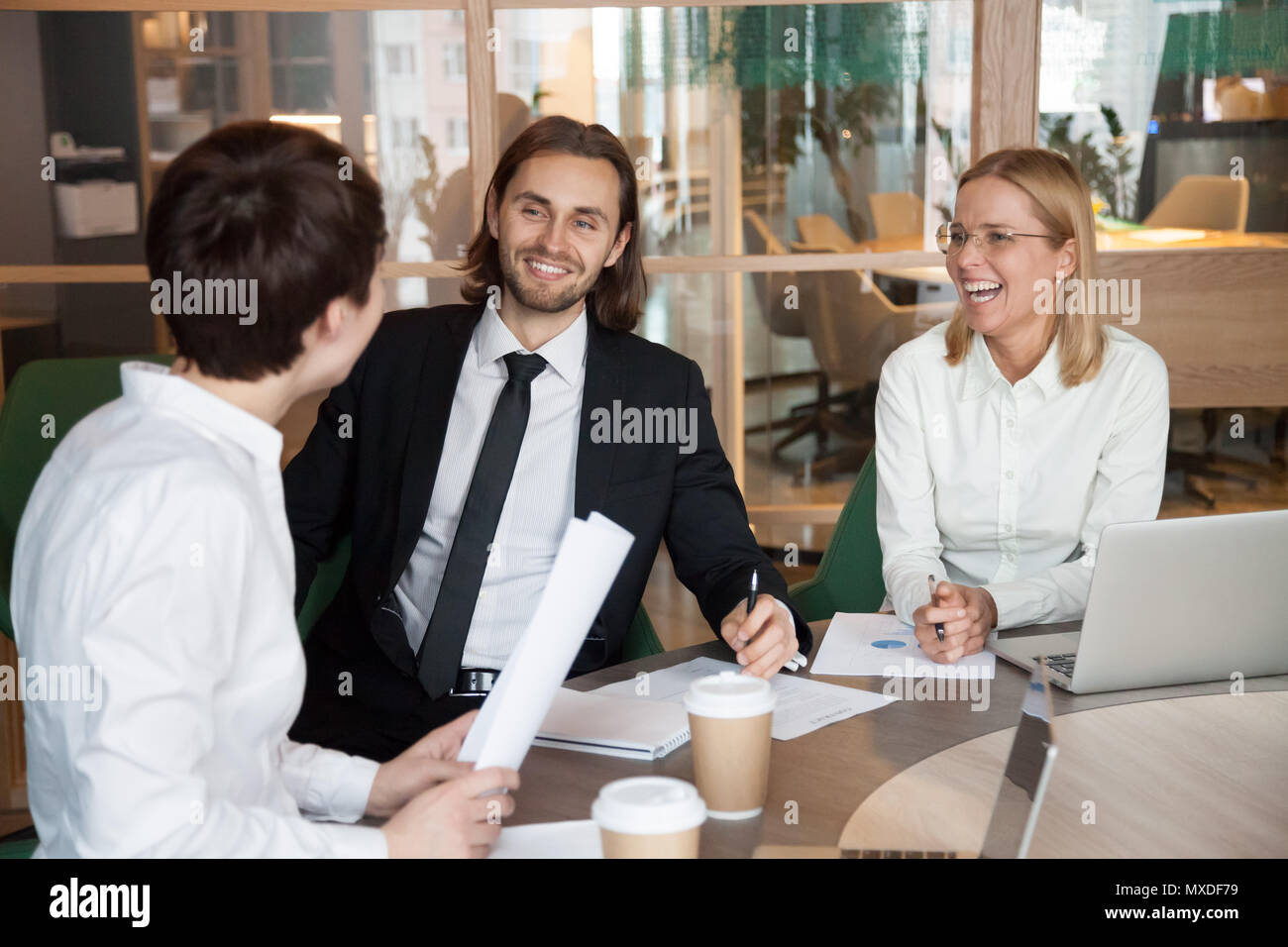 Partners having friendly conversation laughing during business m Stock ...