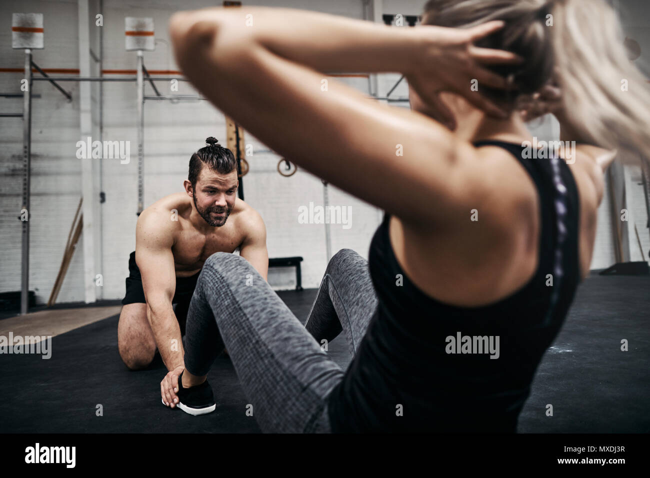 Fit young woman doing sit ups with her male exercise partner on the ...