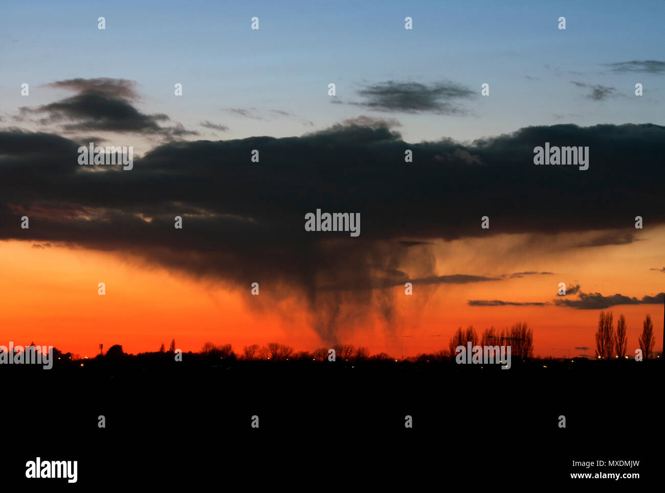 Contrasting red and blue sky with an active rain cloud at dusk Stock ...