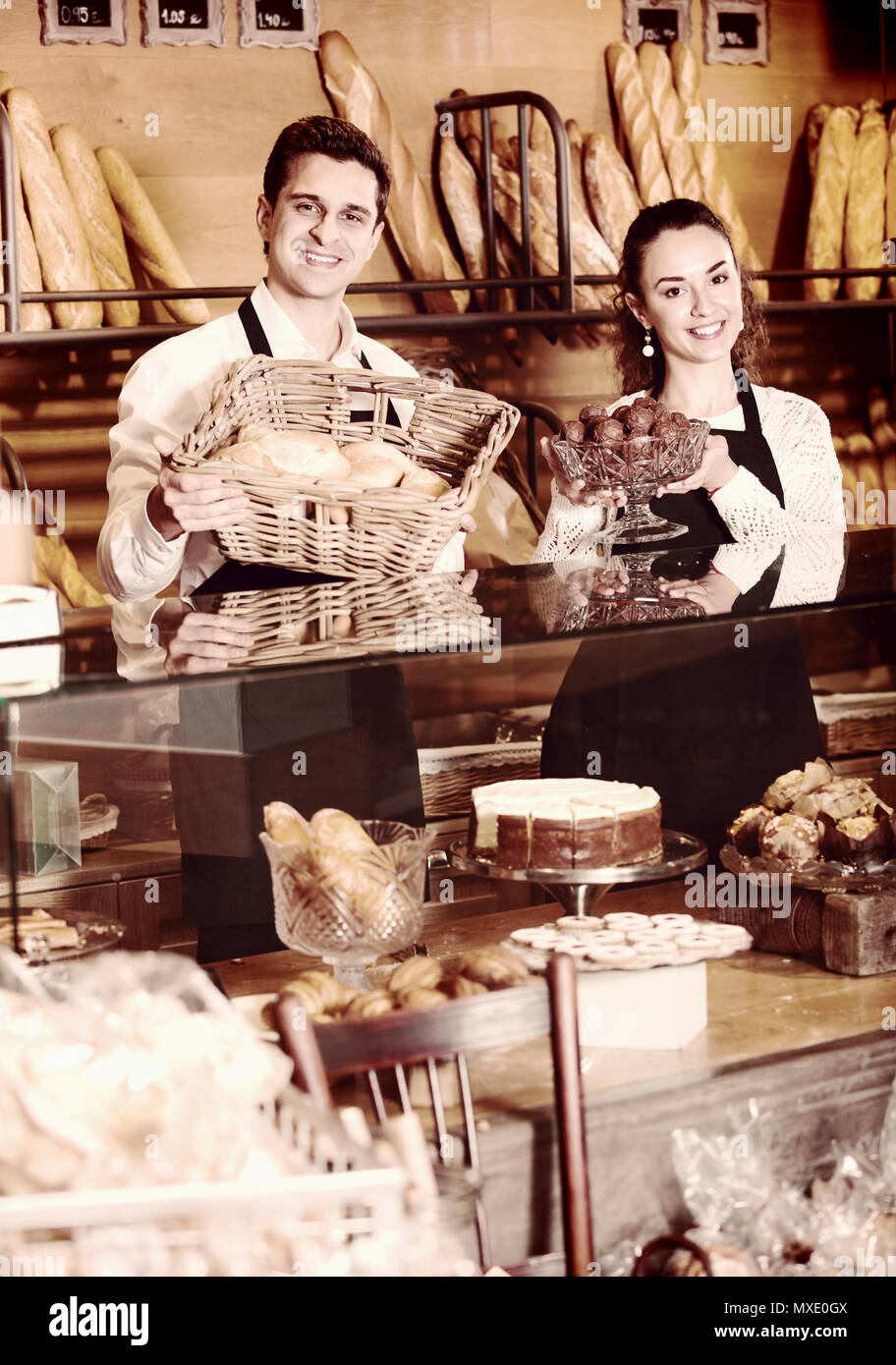 Cafe staff offering fancy and sponge cakes for sale in sweet-shop Stock ...
