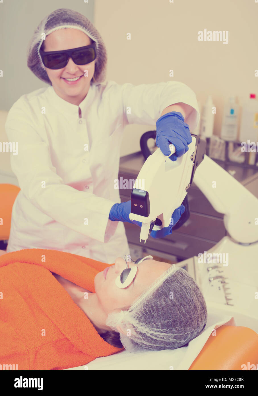 Smiling female client having face hair removed with laser in clinic ...