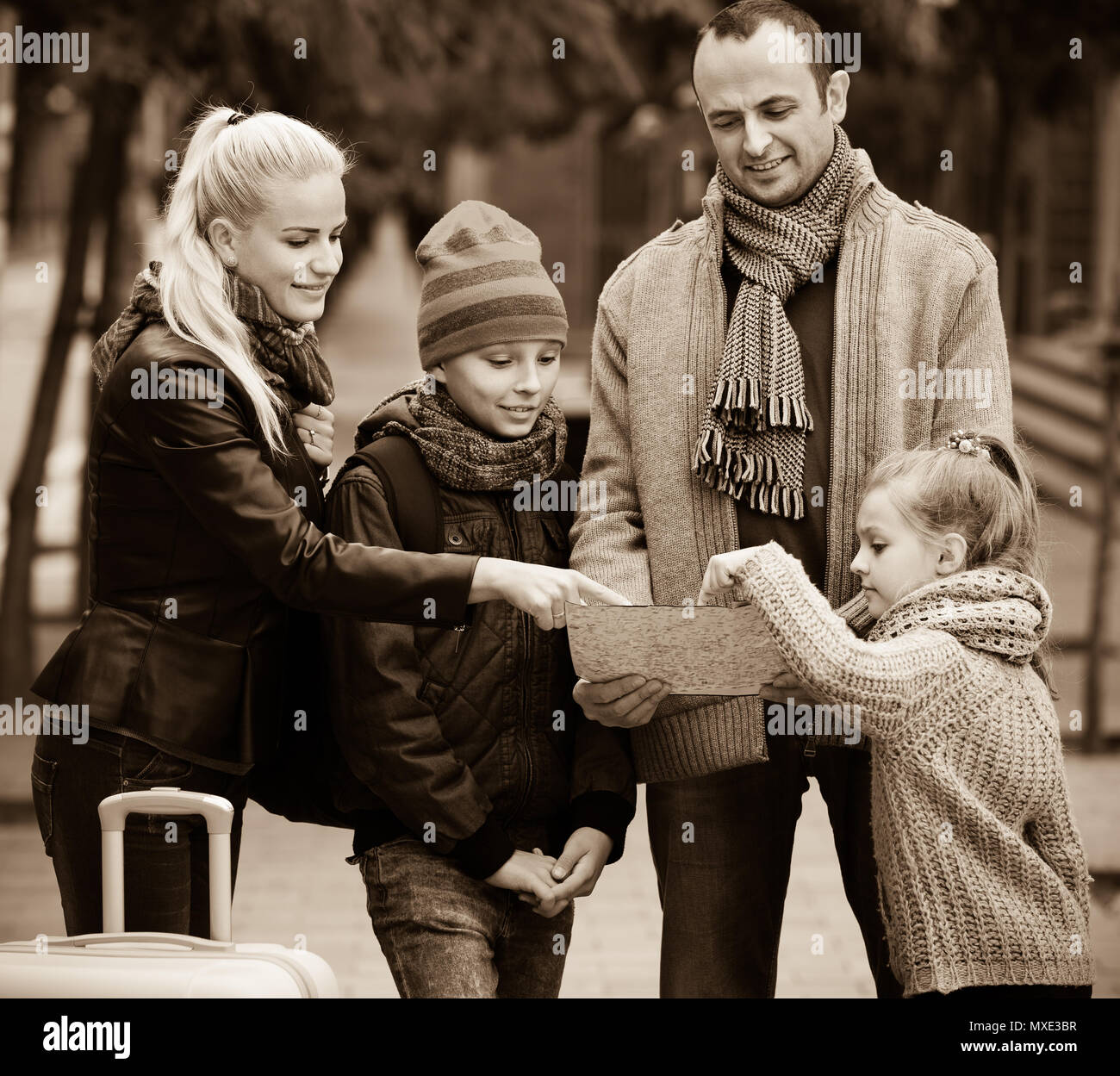 Happy middle class family of four checking direction in map Stock Photo ...