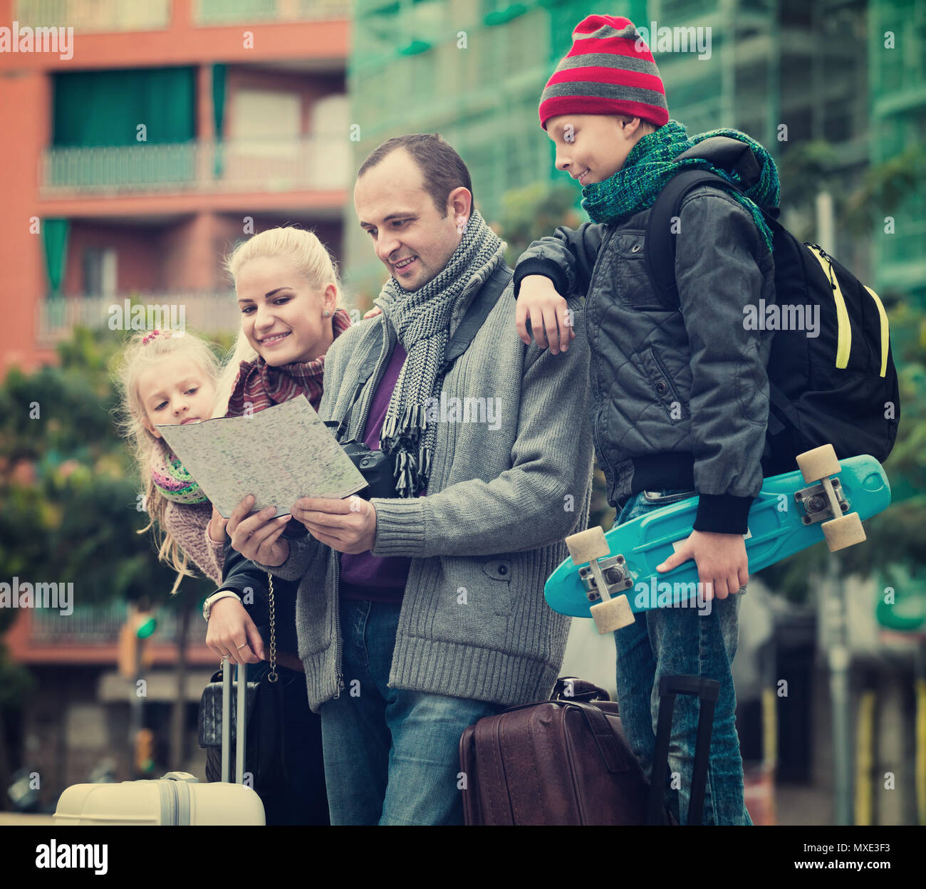Happy middle class family of four checking the direction in a city map ...