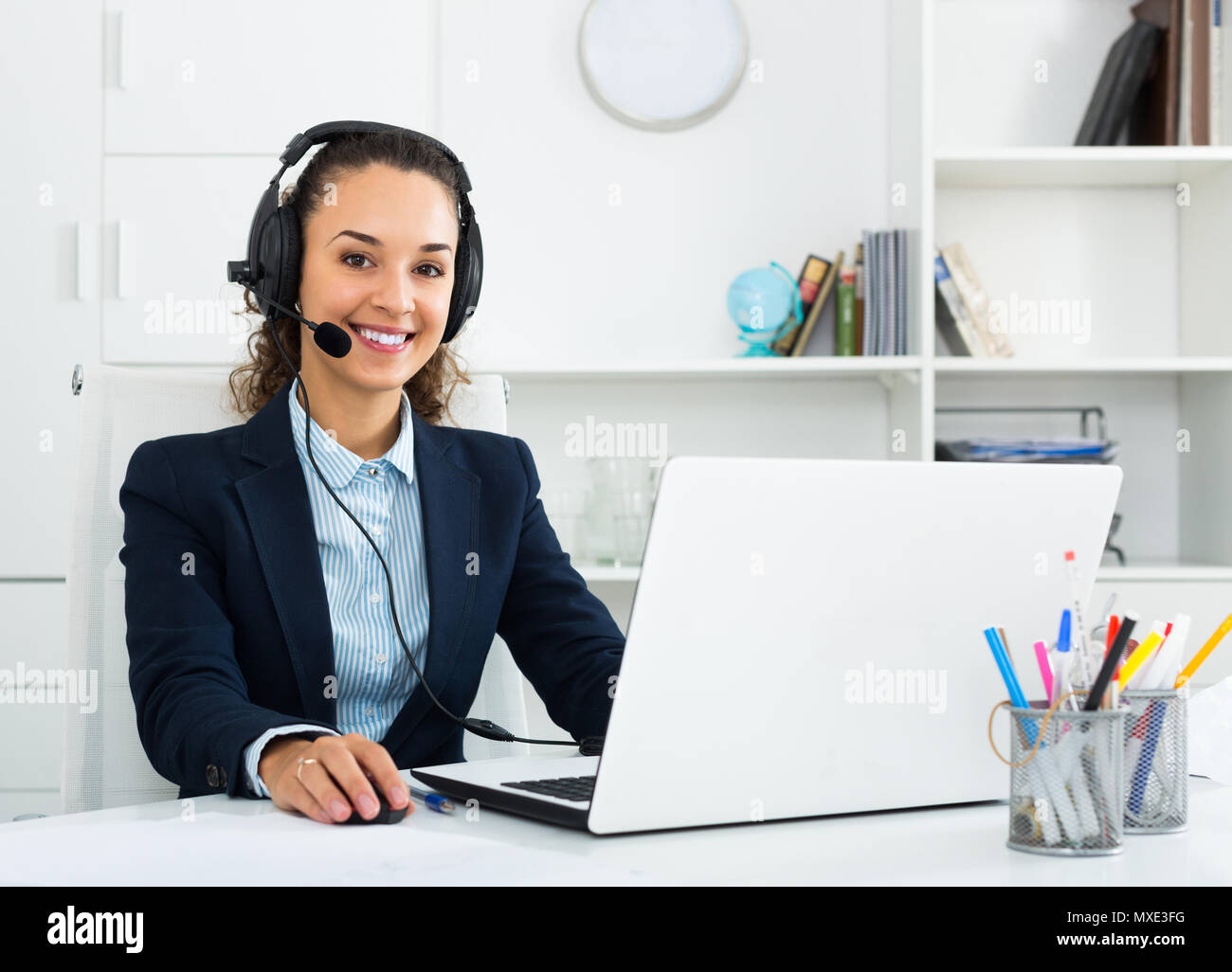 Happy call center operator talking with client by headset and smiling ...