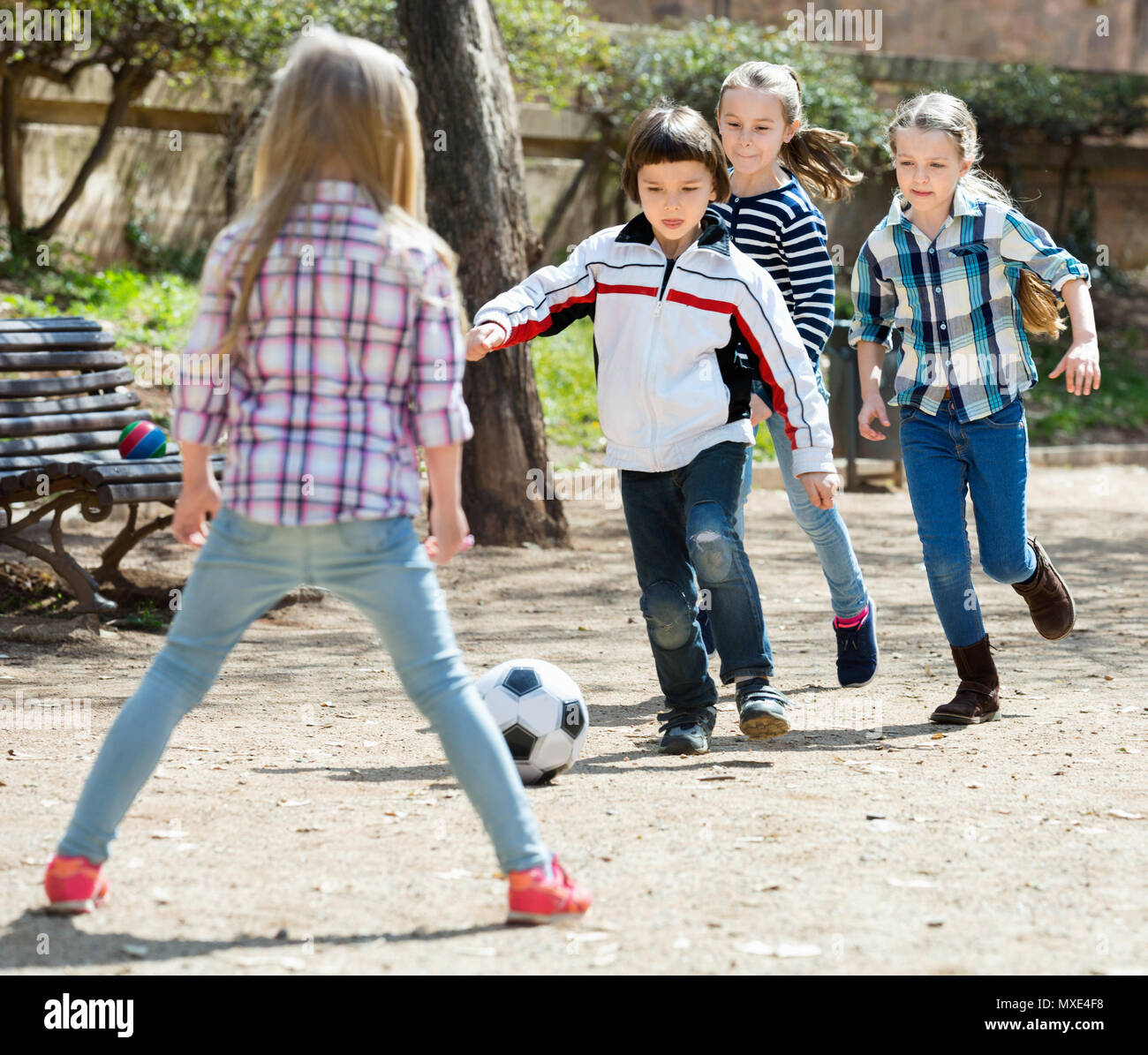 Group of happy children running after ball in urban location Stock ...