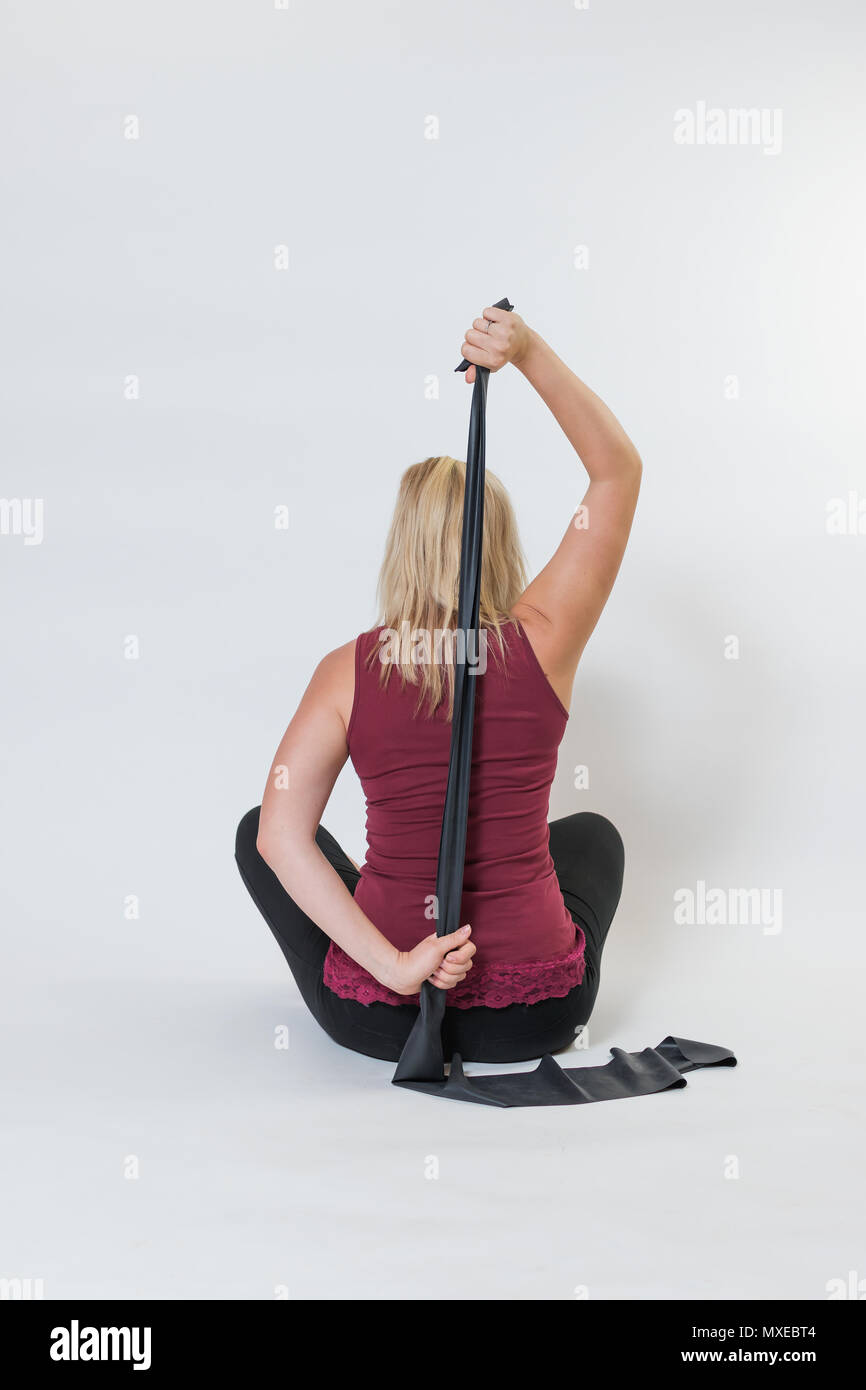 Rear view of a young blond woman sitting and stretching back with a ...