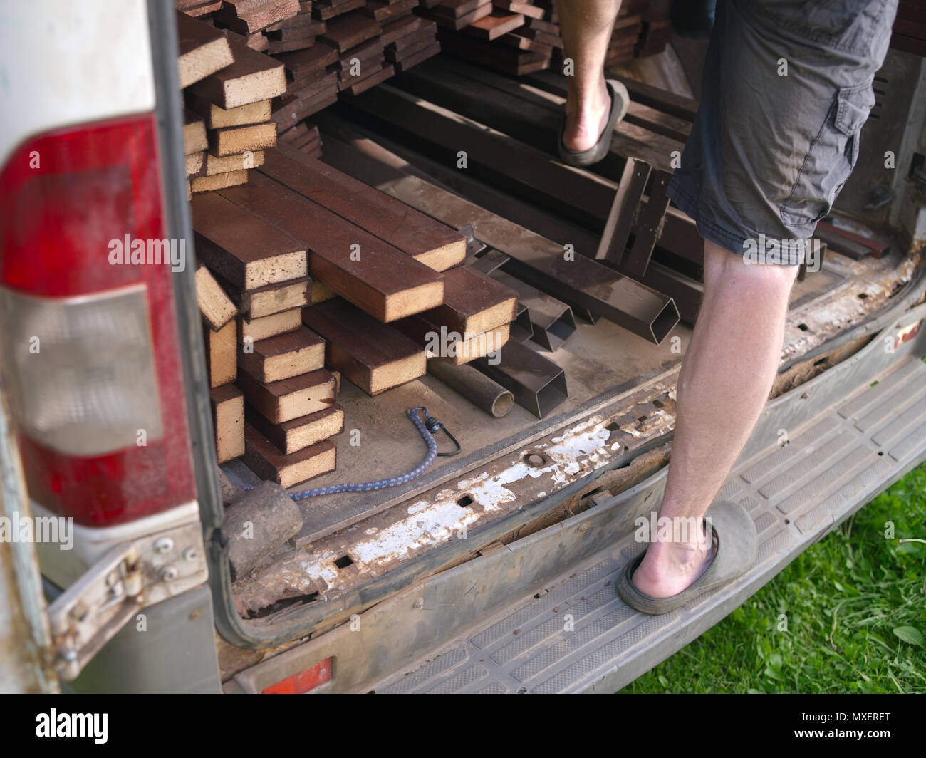 Man standing in a van loaded with wooden planks Stock Photo - Alamy