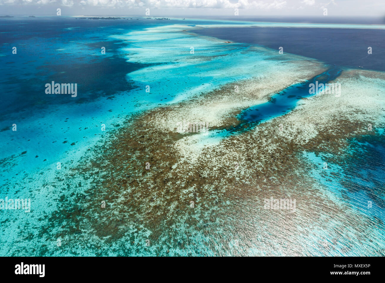 Aerial view of channel cut into a large coral atoll reef system ...