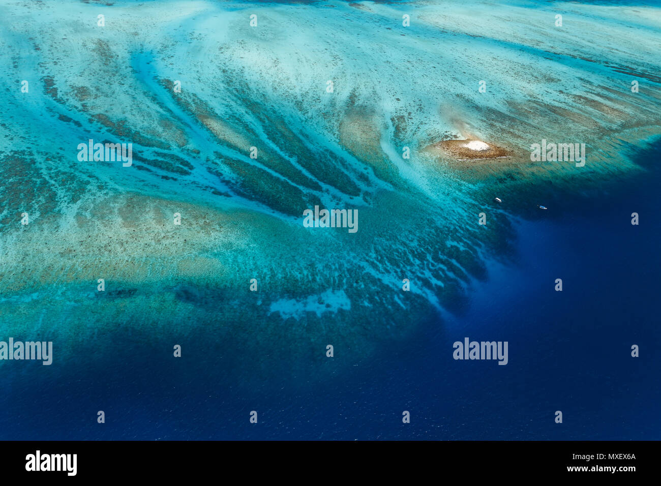 Aerial view of two boats floating above large coral reef separating ...