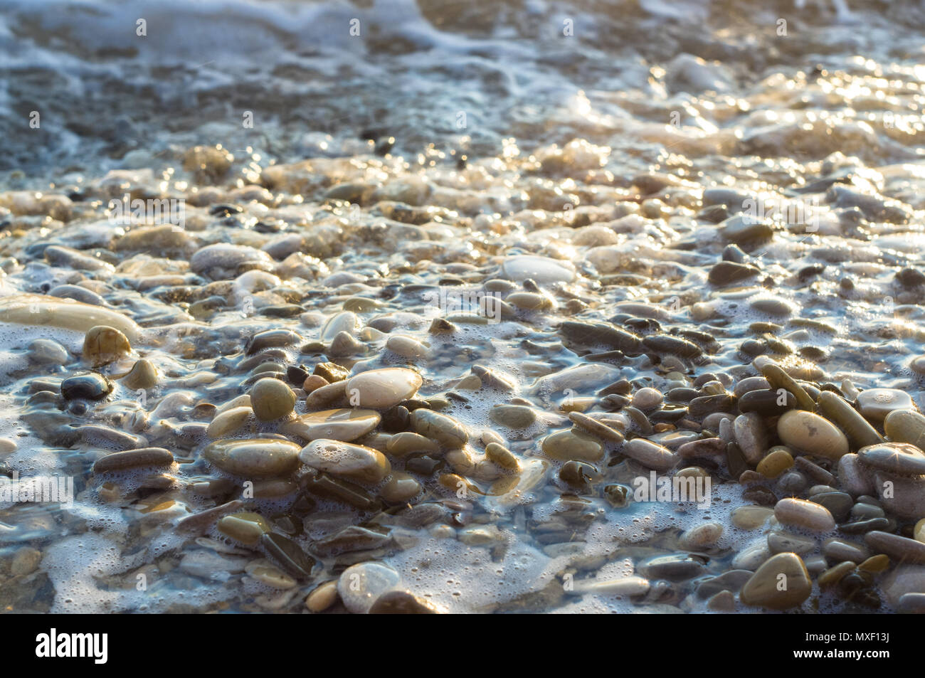 pebble stones on the sea beach, the rolling waves of the sea with foam ...