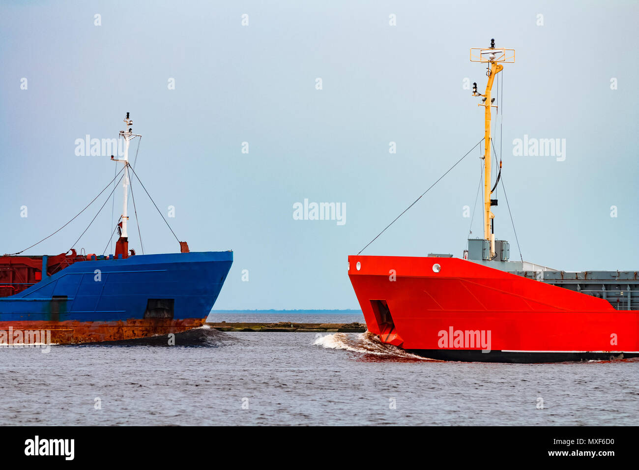 Orange cargo ship sailing past the blue bulk carrier Stock Photo - Alamy