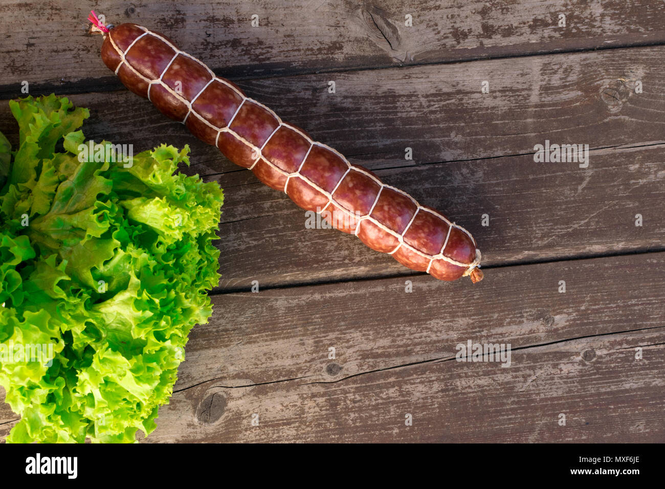 italian salami on ancient wood table with green lettuce Stock Photo - Alamy