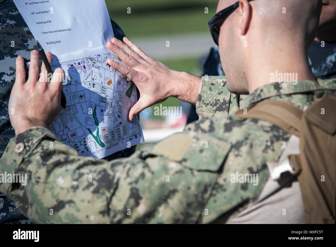 A sailor reviews a map during the land navigation portion of the ...