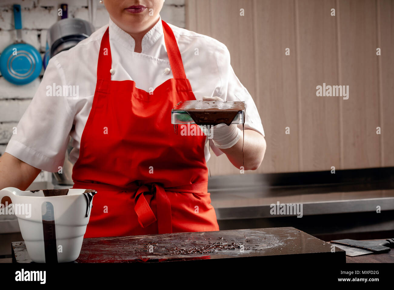 A woman confectioner with red uniform and white sterile gloves do a set ...