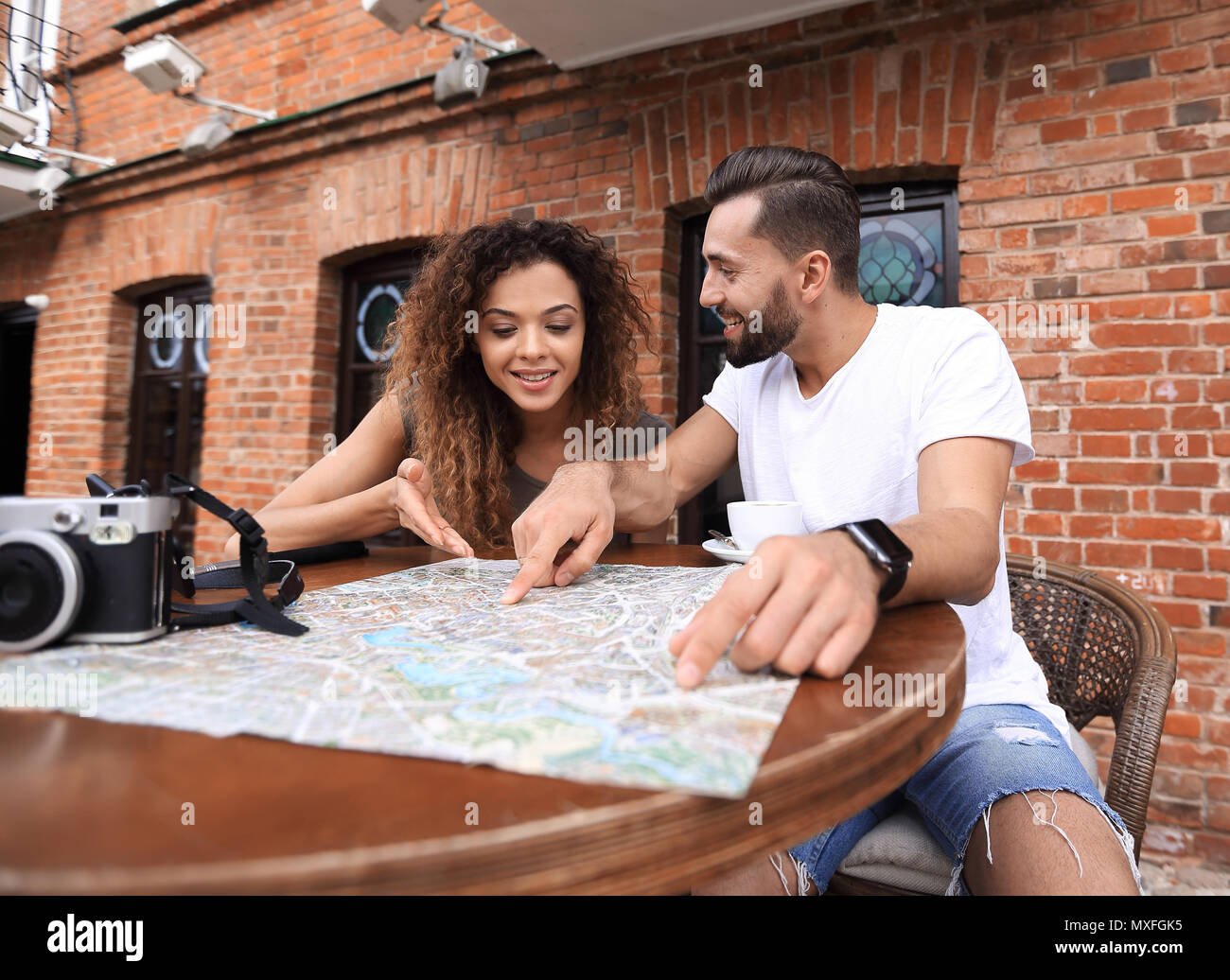 Young tourists drinking coffee at cafe and reading city map Stock Photo ...