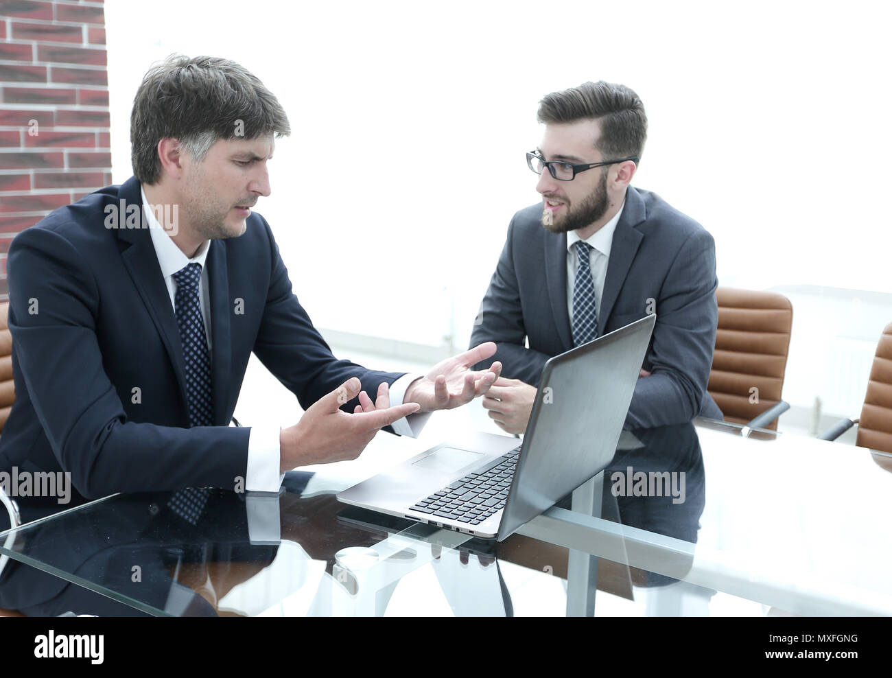 Two businessmen discussing tasks sitting at office table Stock Photo ...
