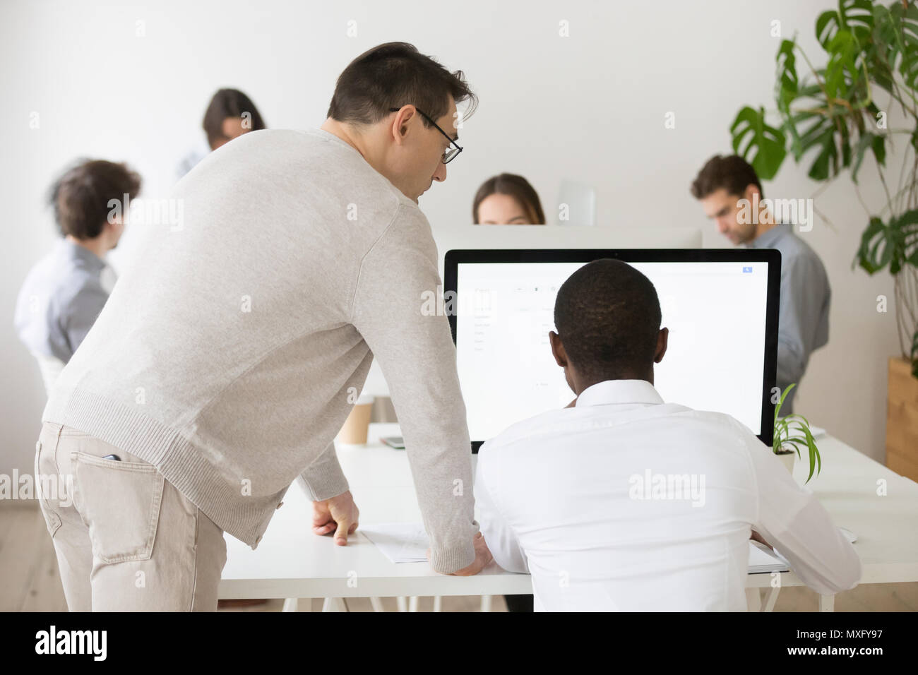 Senior mentor helping African American colleague with pc Stock Photo ...