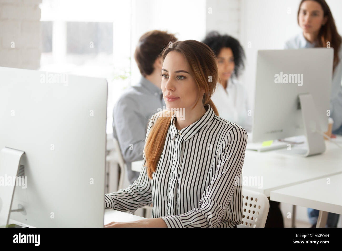 Attractive female worker working at computer in office Stock Photo - Alamy