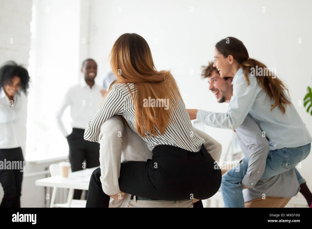 Laughing colleagues having piggyback ride at office Stock Photo - Alamy