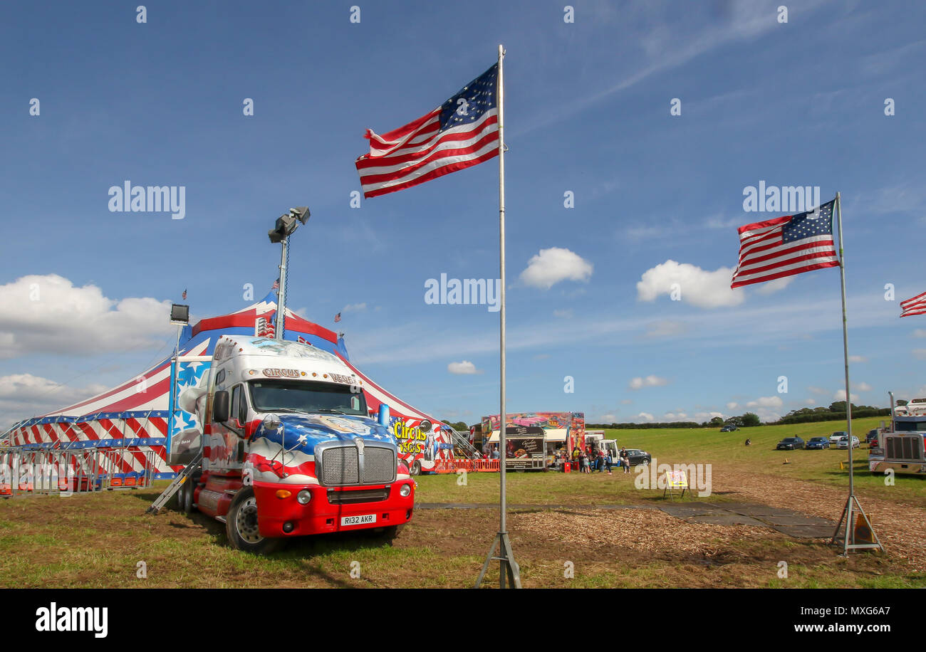 Multi-coloured circus truck beside American coloured circus tent ...