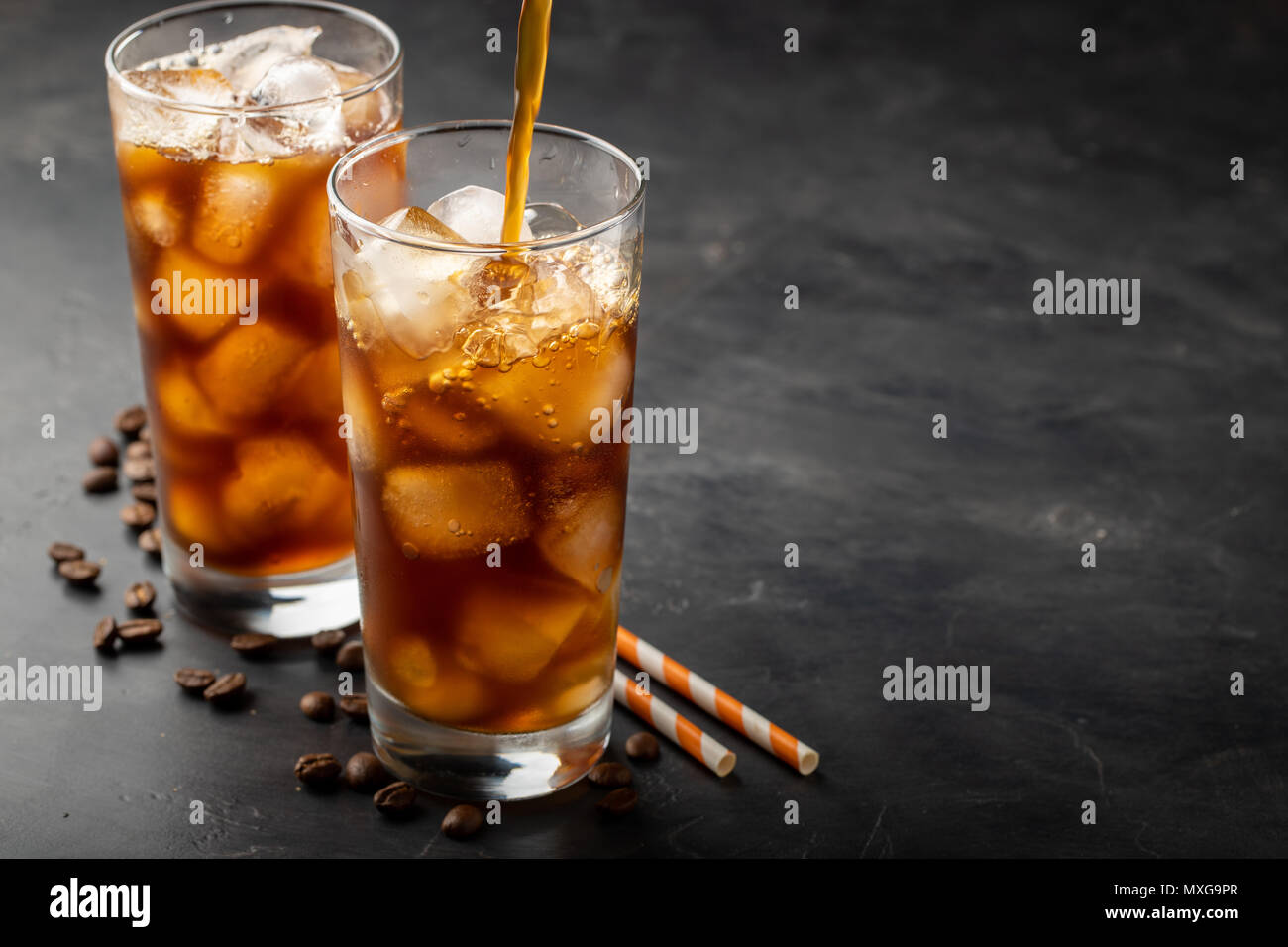 Ice coffee in a tall glass over and coffee beans on a old rustic wooden ...