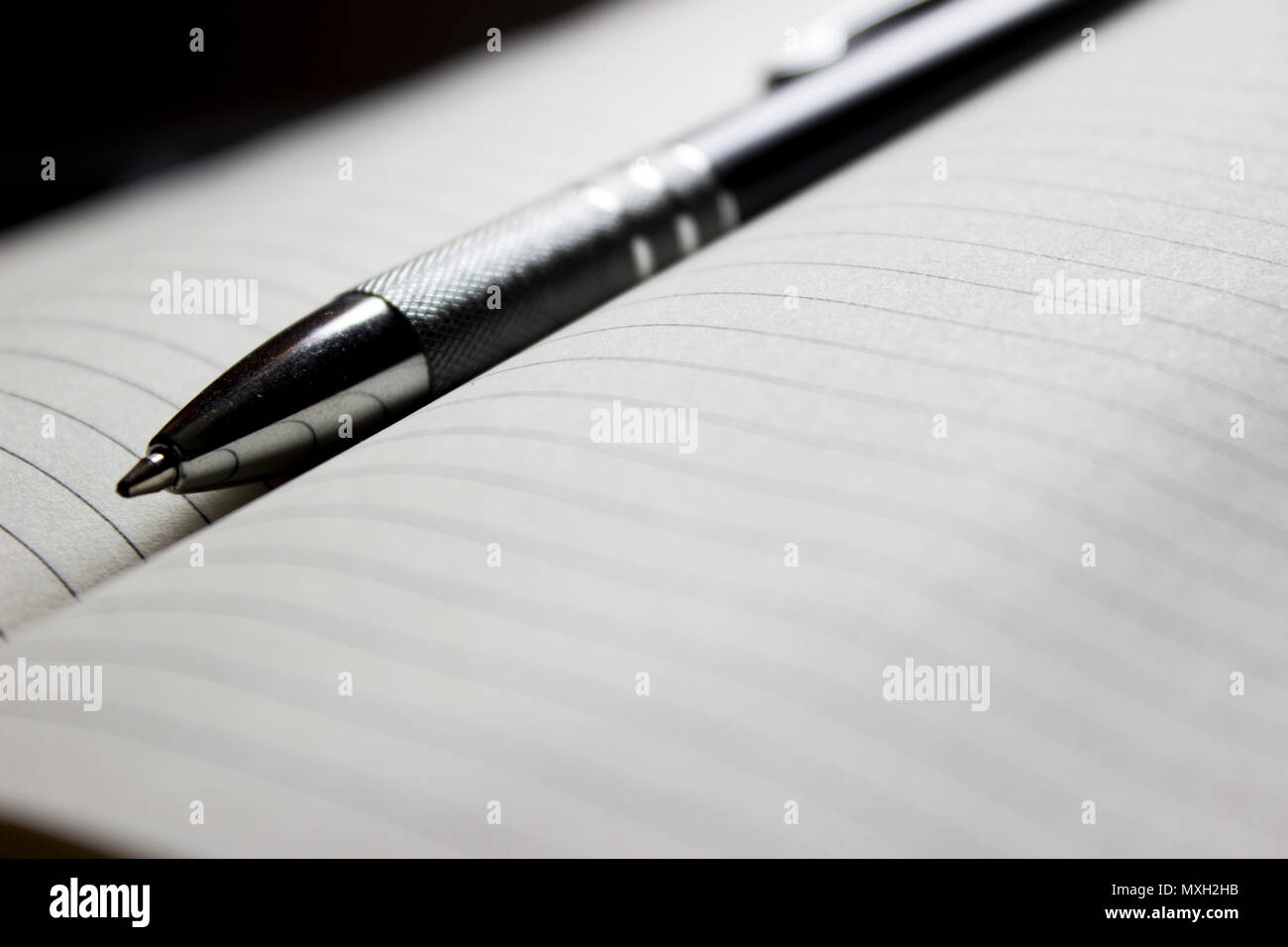 Pen laying over notebook Stock Photo - Alamy