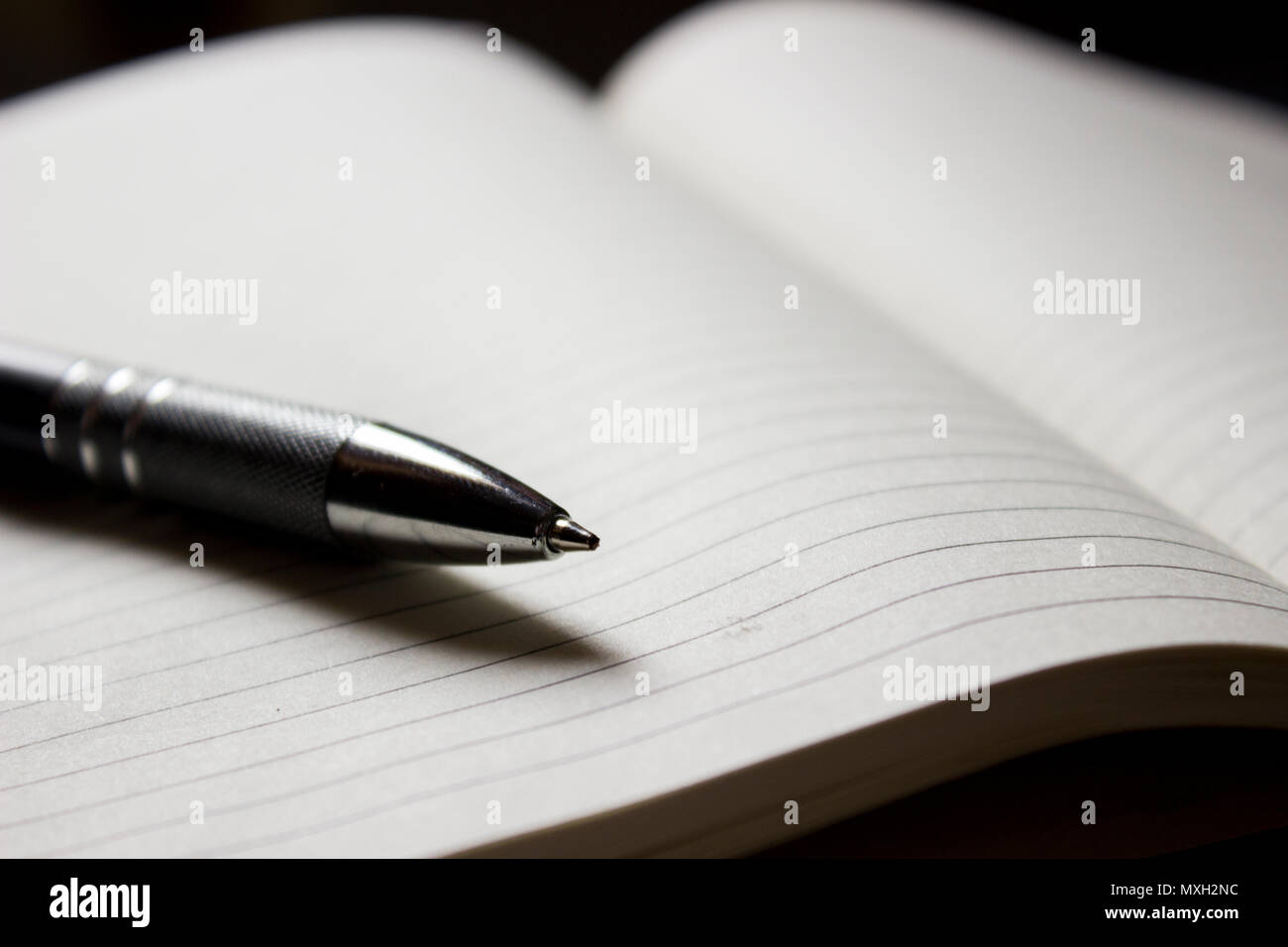 Pen laying over notebook Stock Photo - Alamy