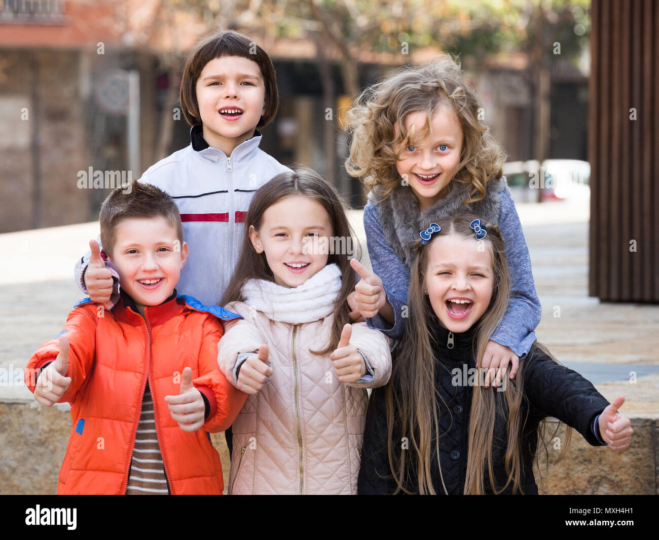 Smiling little kids showing thumbs up in city street Stock Photo - Alamy