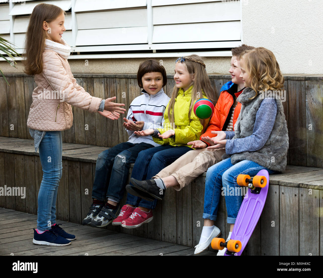Beautiful group of children sitting on bench and playing with ball ...