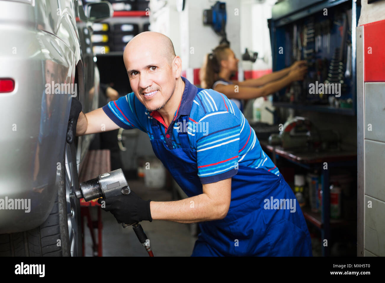 Happy mechanic man working with impact tire fitting tool in service ...