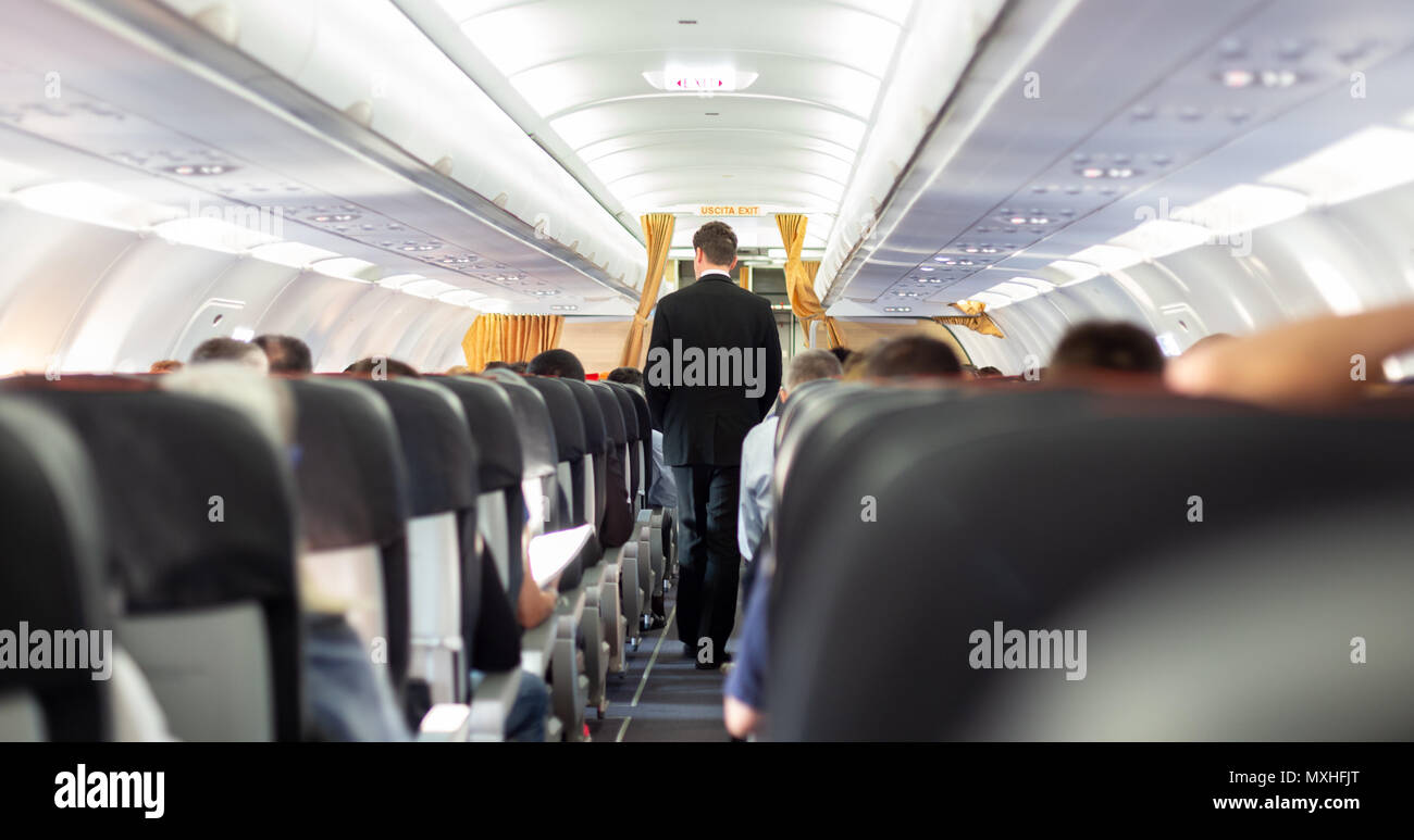 Interior of commercial airplane with steward walking the aisle Stock ...