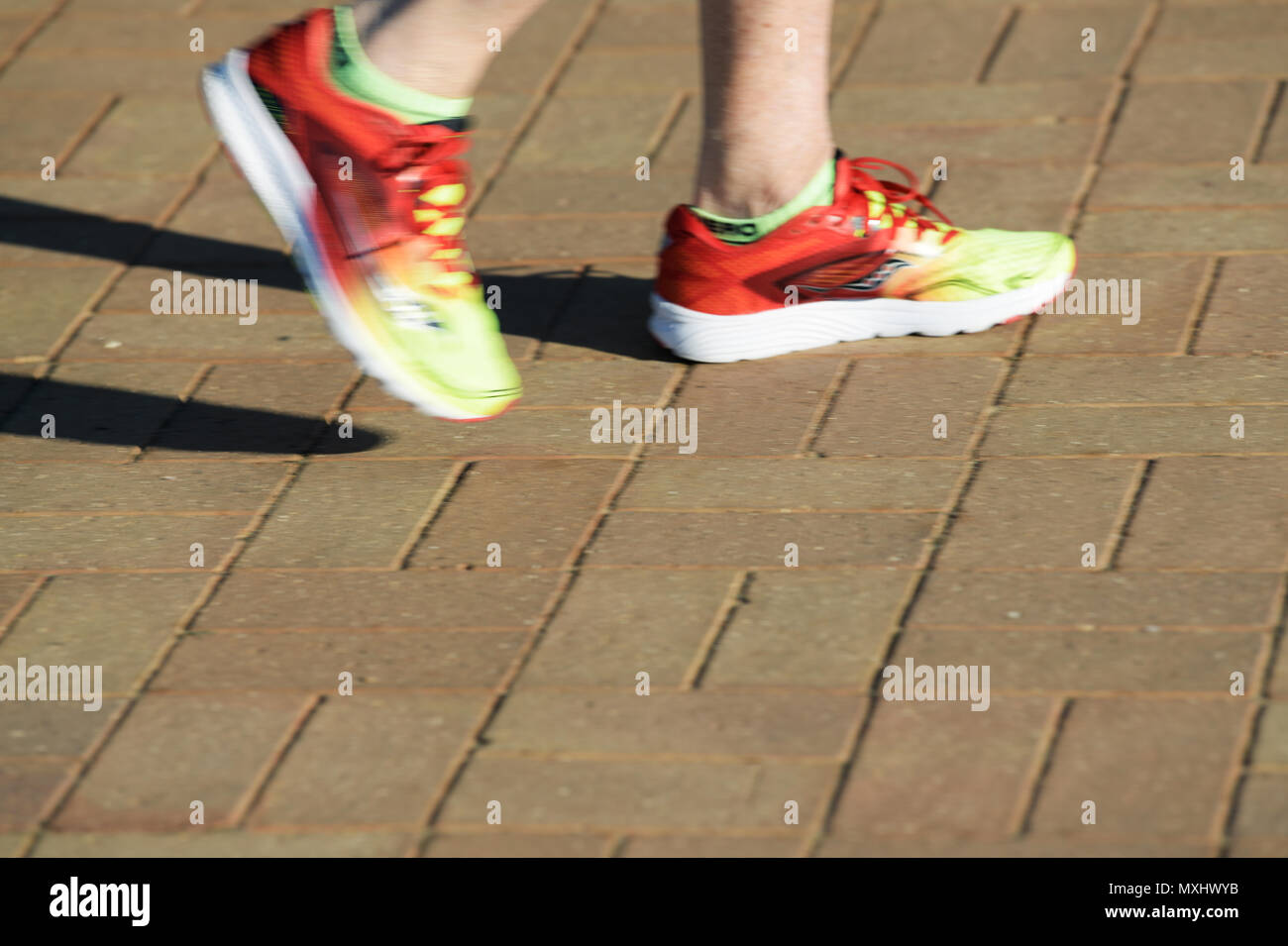 Colourful running shoes on the feet of an adult man taking a stride ...