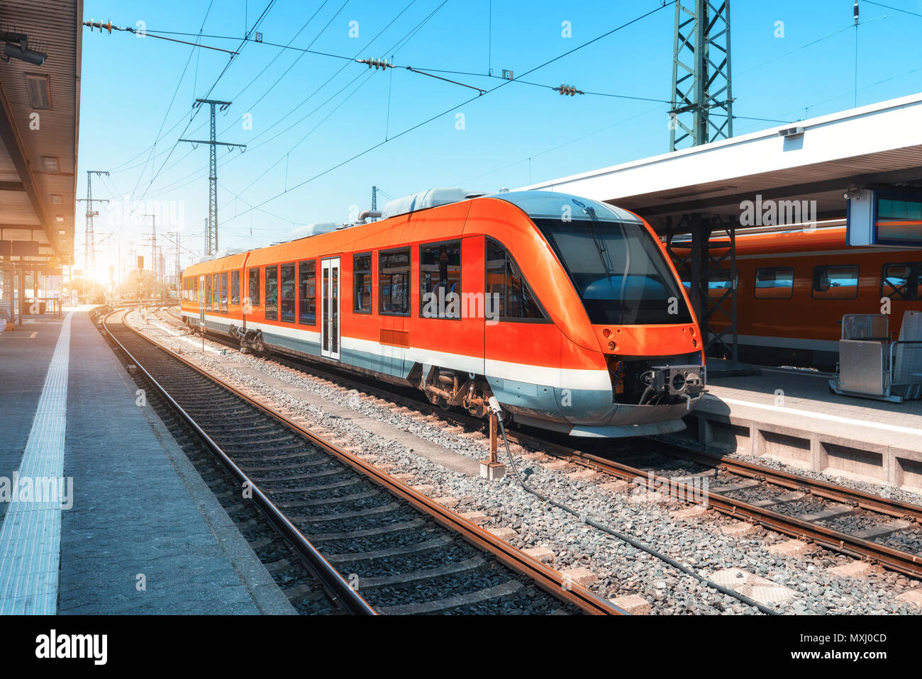 High speed red train on the railway station at sunset in summer. Modern ...
