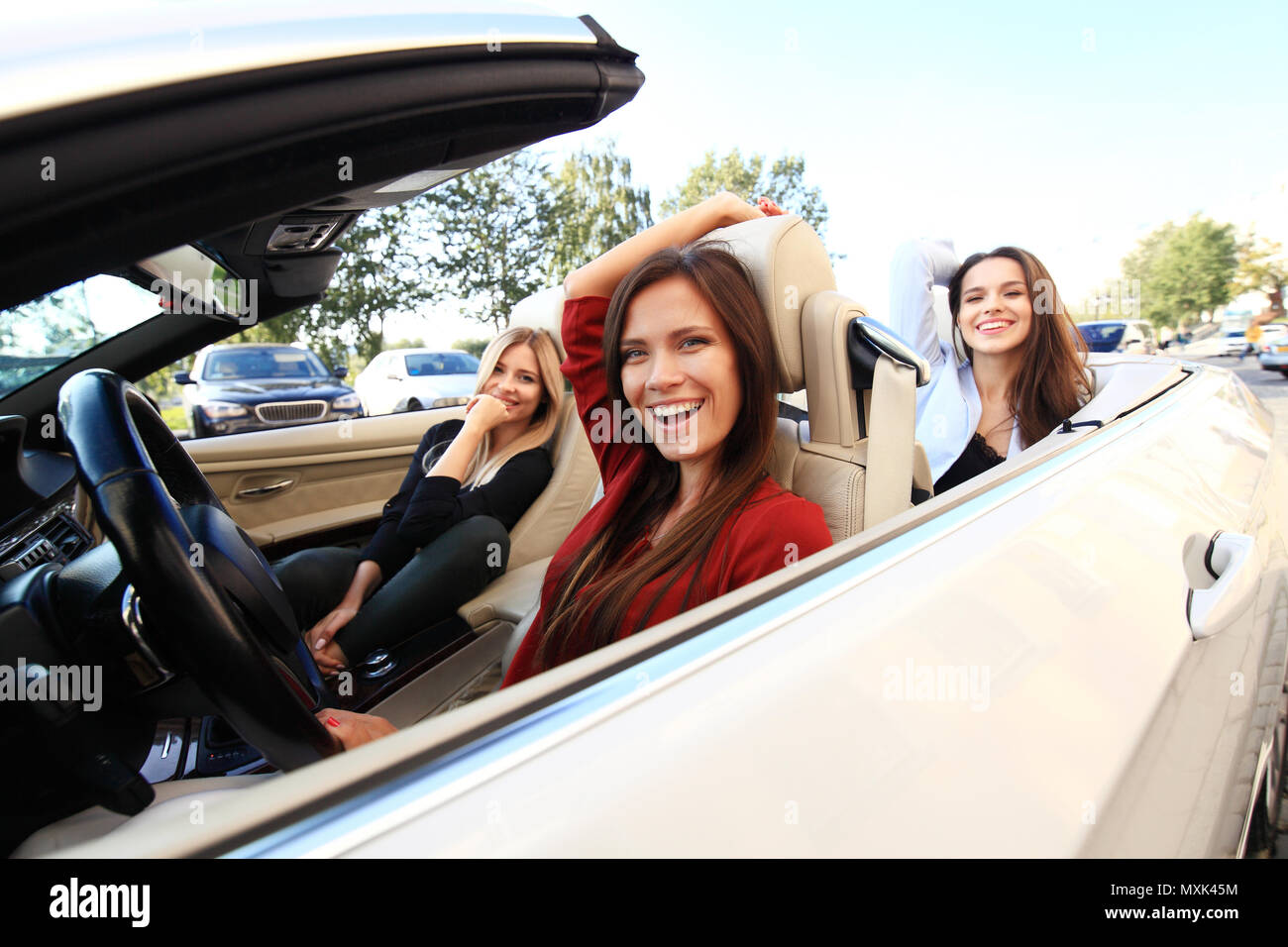 three girls driving in a convertible car and having fun Stock Photo - Alamy