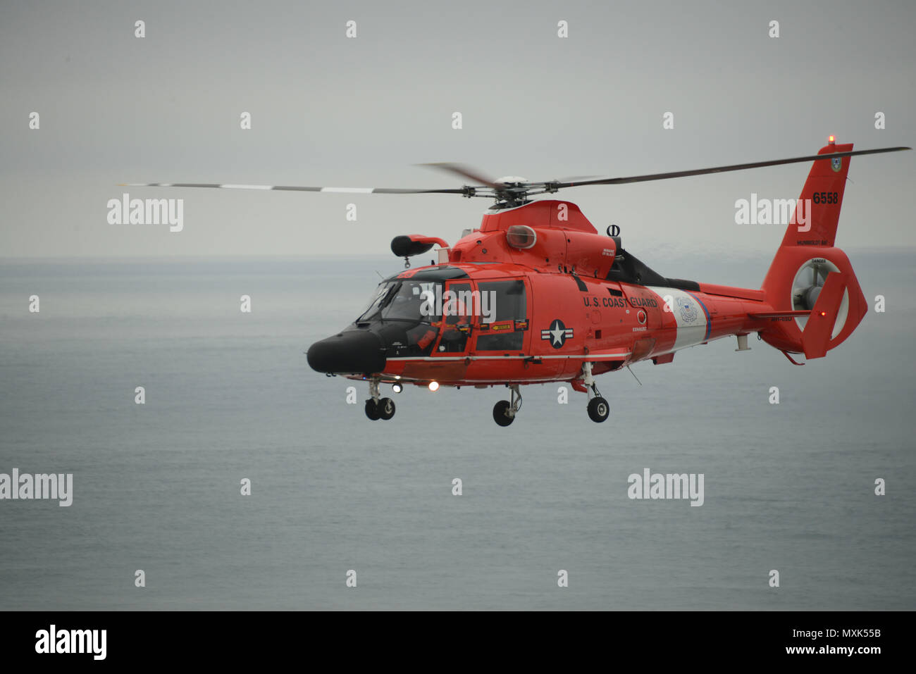 An aircrew aboard an MH-65 Dolphin helicopter flies near the North Head ...