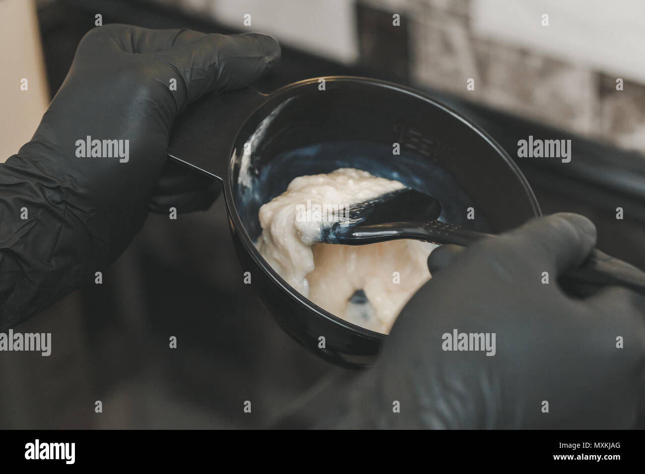 Stylist preparing a hair dye in a container, hairdresser salon concept ...