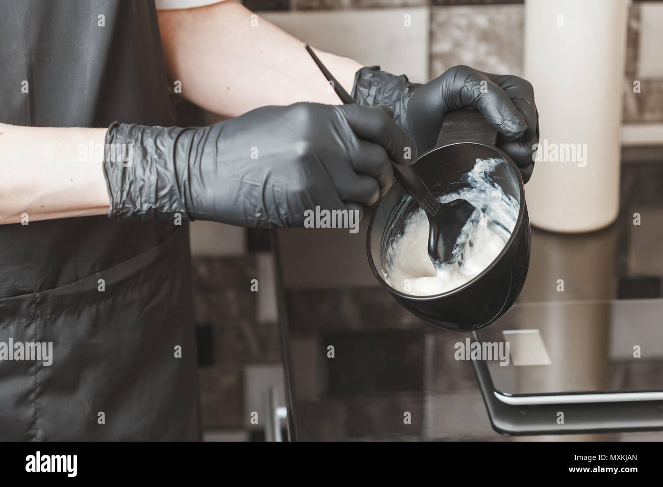 Stylist preparing a hair dye in a container, hairdresser salon concept ...