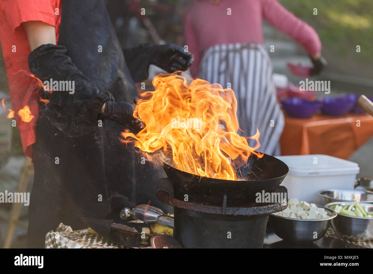 Cooking asian food in flaming cast iron wok. Street food concept Stock ...