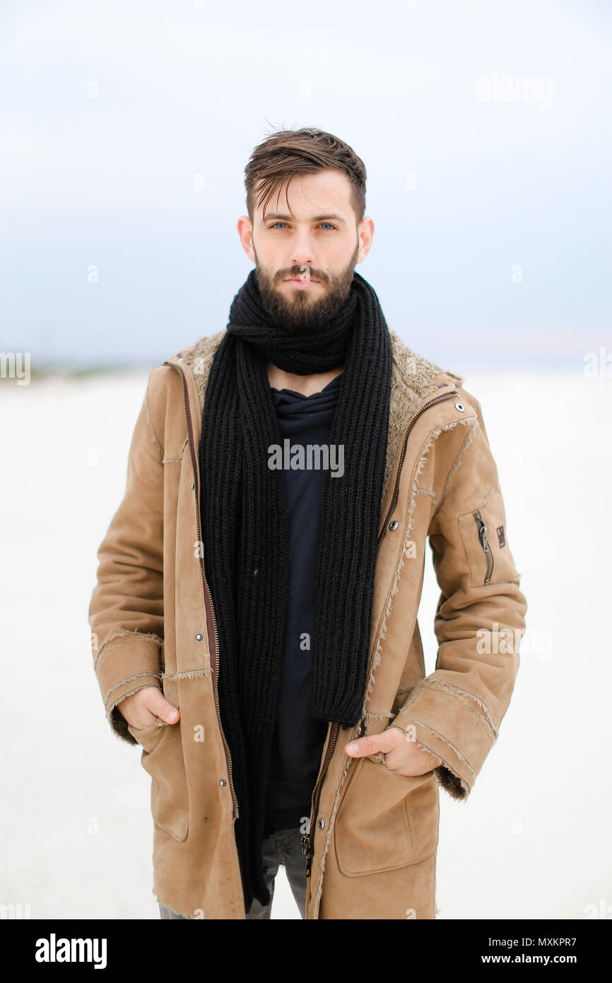 European stylish male person with beard wearing coat and scarf standing ...