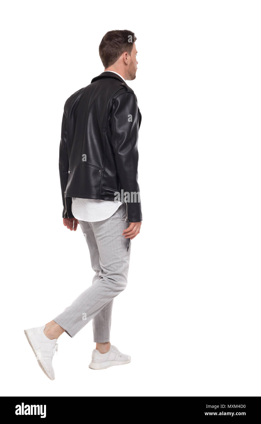 Back view of going handsome man in a leather jacket and trousers ...