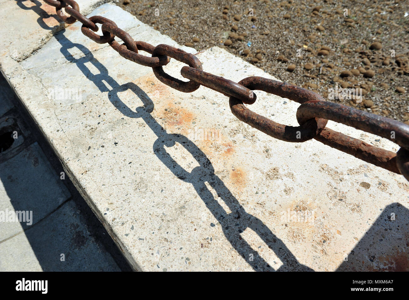 Strong, solid rusty chain shot from above in sunlight. Shadow from the ...