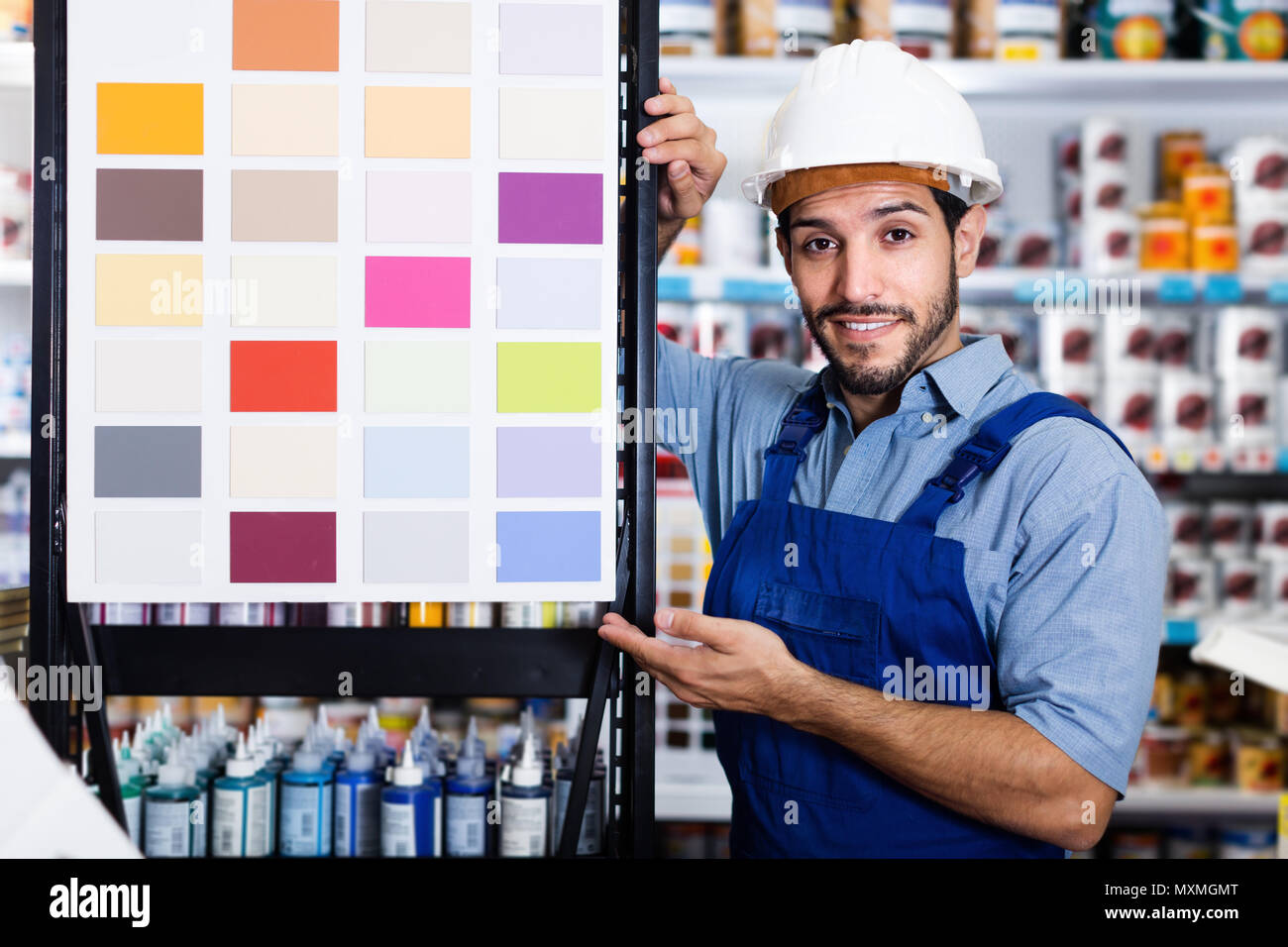 Happy workman offering to choose color of coating on stand with samples ...