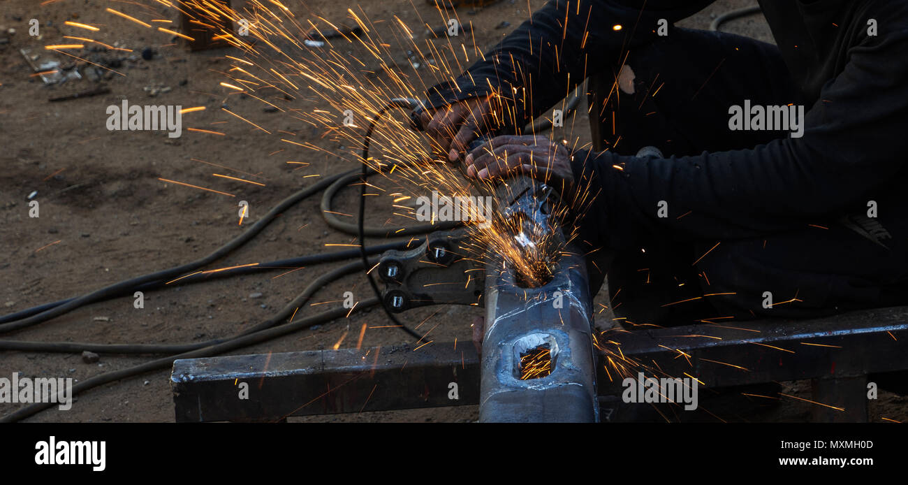 Metal work. Man grinds a steel piece with an angle grinder Stock Photo ...