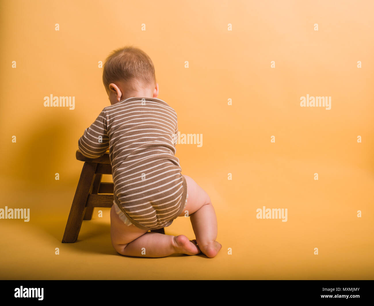 A little baby is learning to stand up using a stool Stock Photo - Alamy