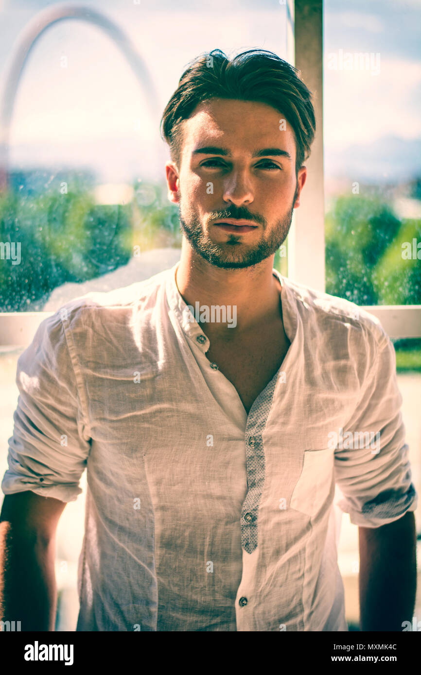 Serious young man standing inside modern building Stock Photo - Alamy